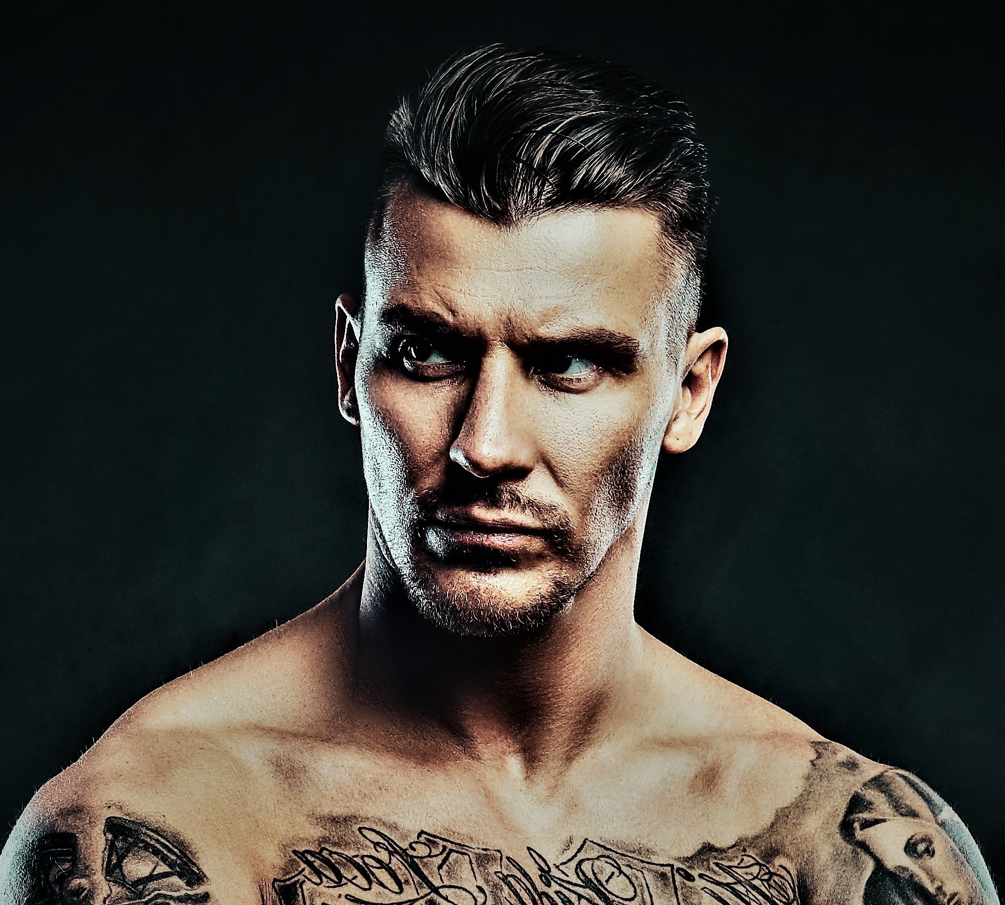 A muscular tattooed man over dark background. – The Red Room