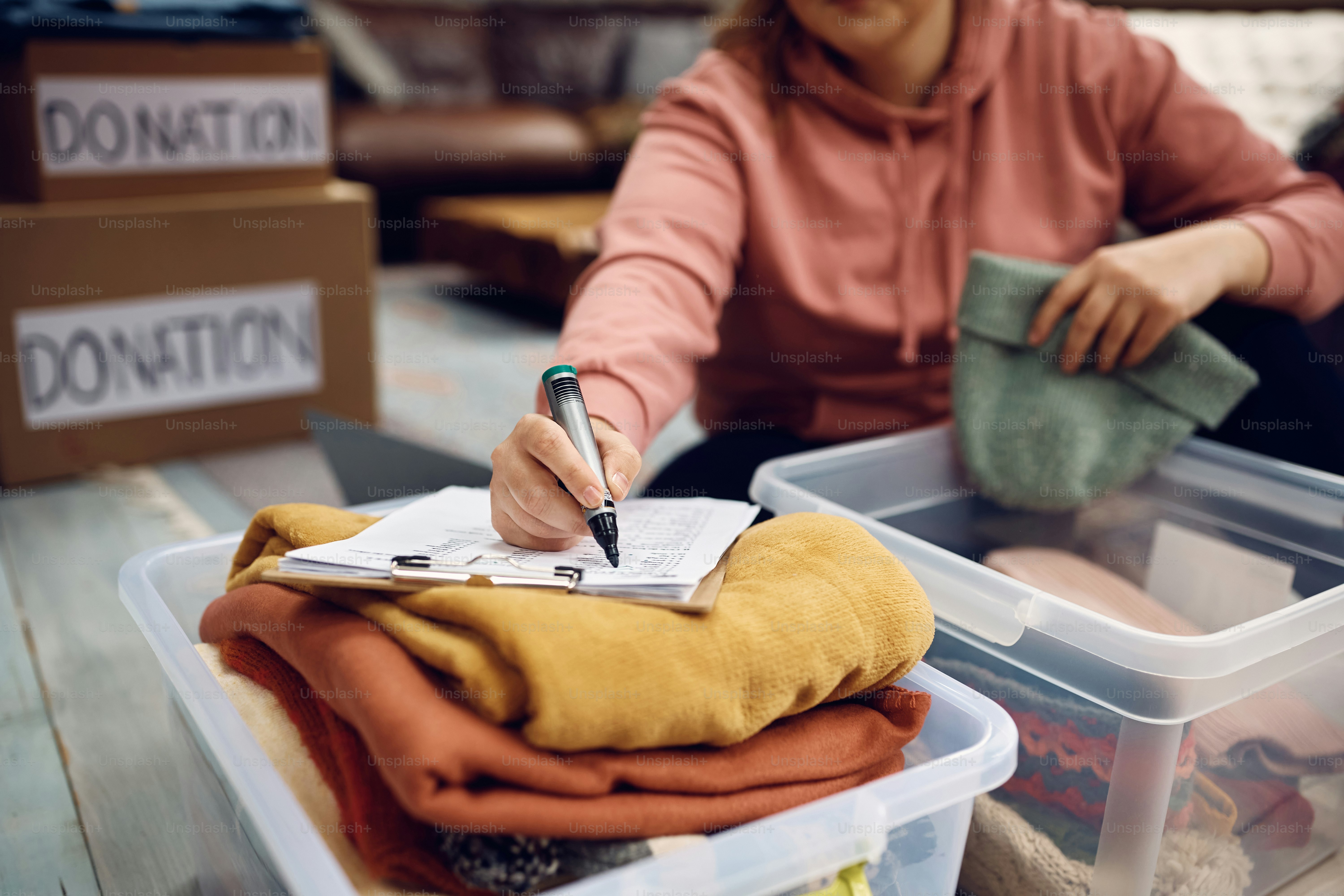 Close Up Of Woman Checking List Of Donated Clothes For Charity While