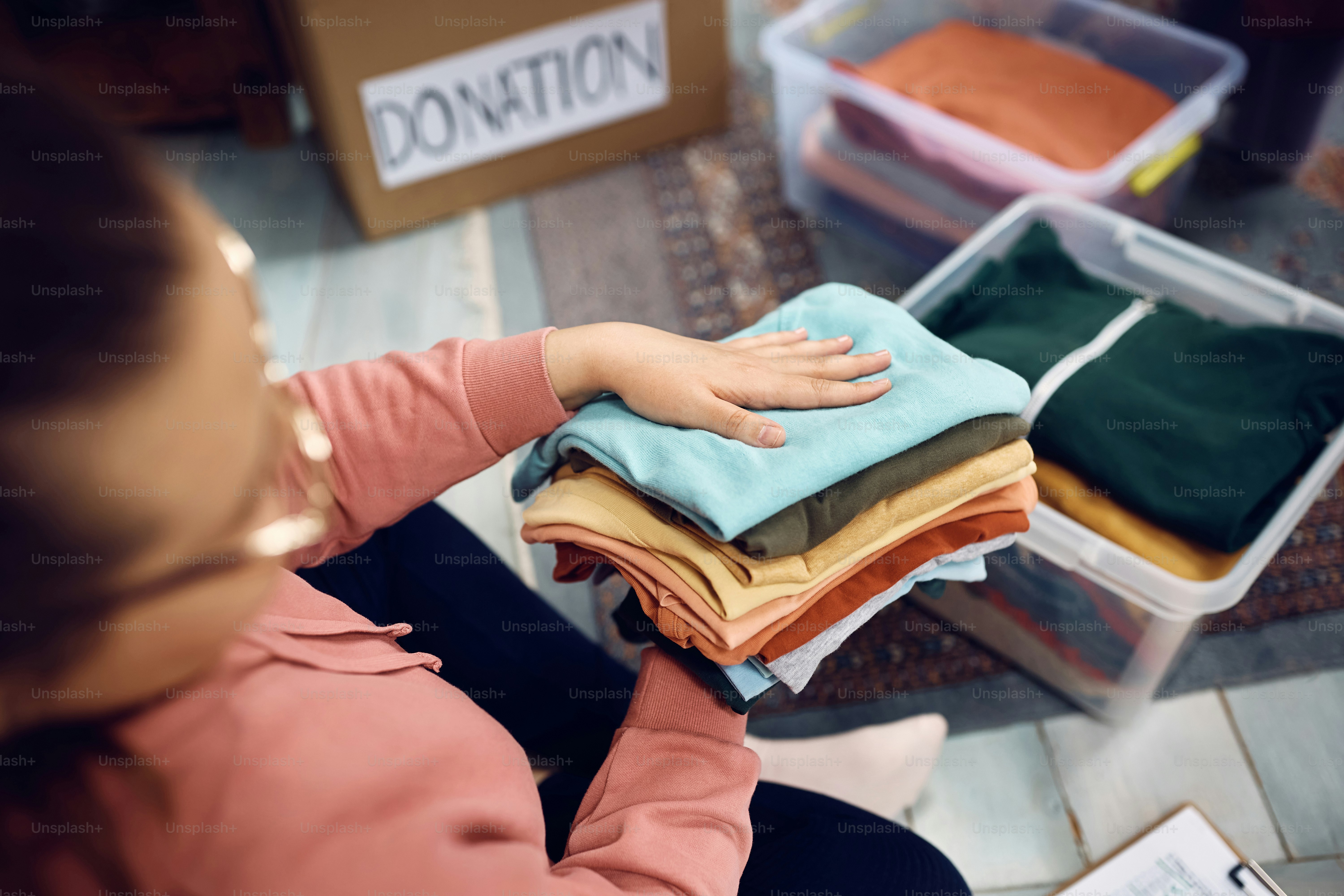 Close Up Of Woman Checking List Of Donated Clothes For Charity While