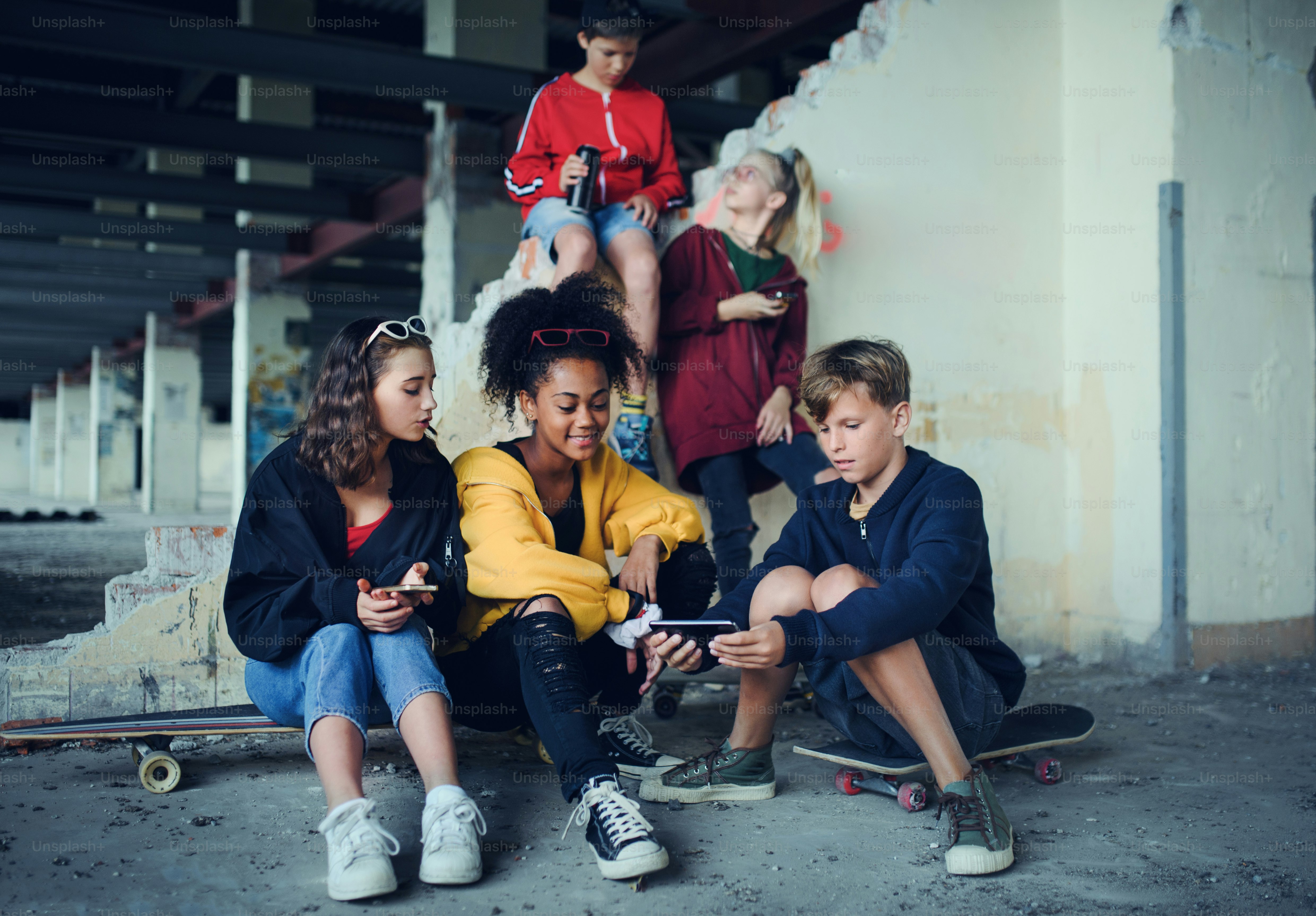 Front View Of Group Of Teenagers Gang Sitting Indoors In Abandoned