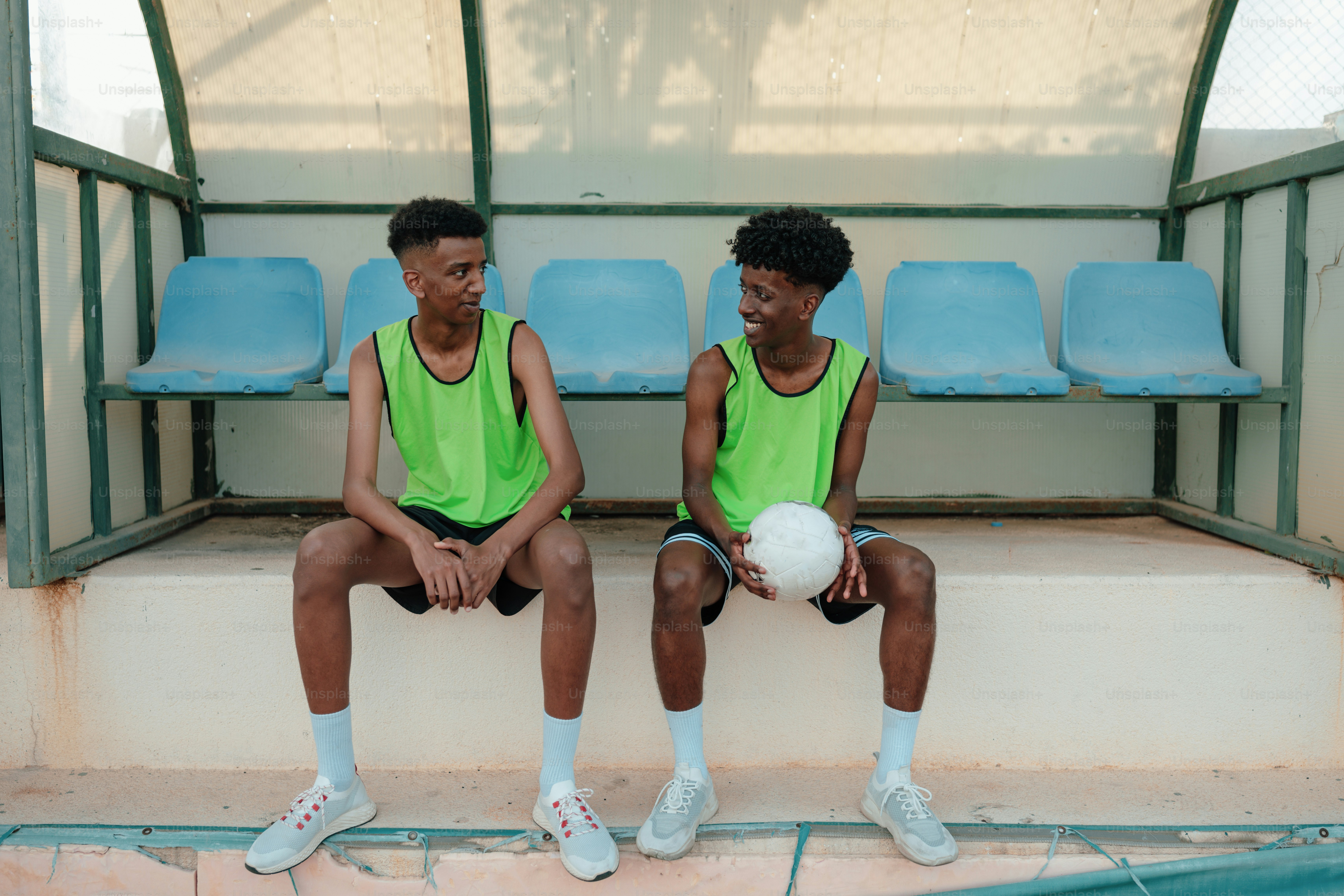 Dos Jóvenes Sentados En Un Banco Con Una Pelota Foto Imagen De Fútbol